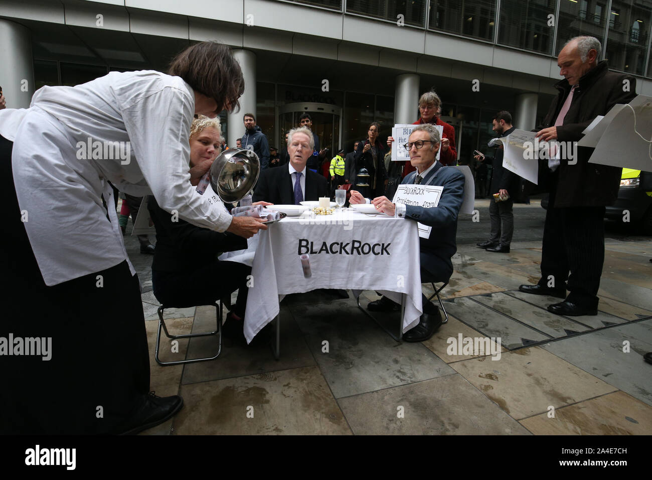 Protesters 'eat money' as a form of demonstration outside the BlackRock ...