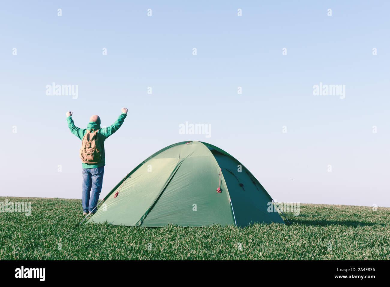 Tourist with hands up near his tent on summer field. Travel concept ...