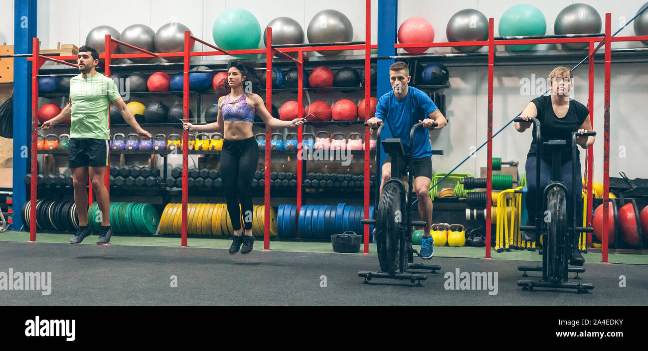 Athletes doing air bike and skipping rope Stock Photo - Alamy
