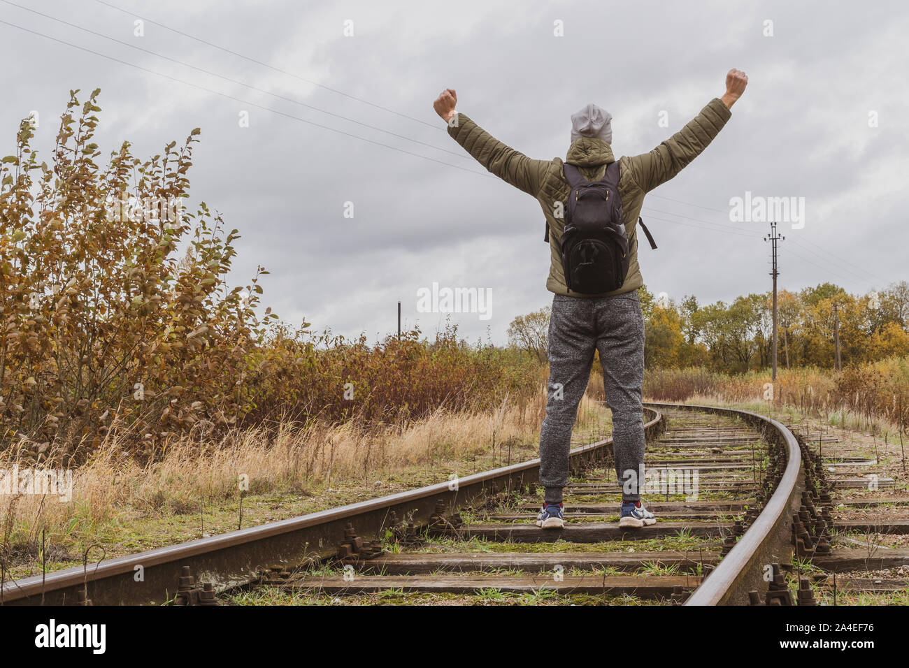 Man standing on the railway and raising hands up. Rear view Stock Photo ...