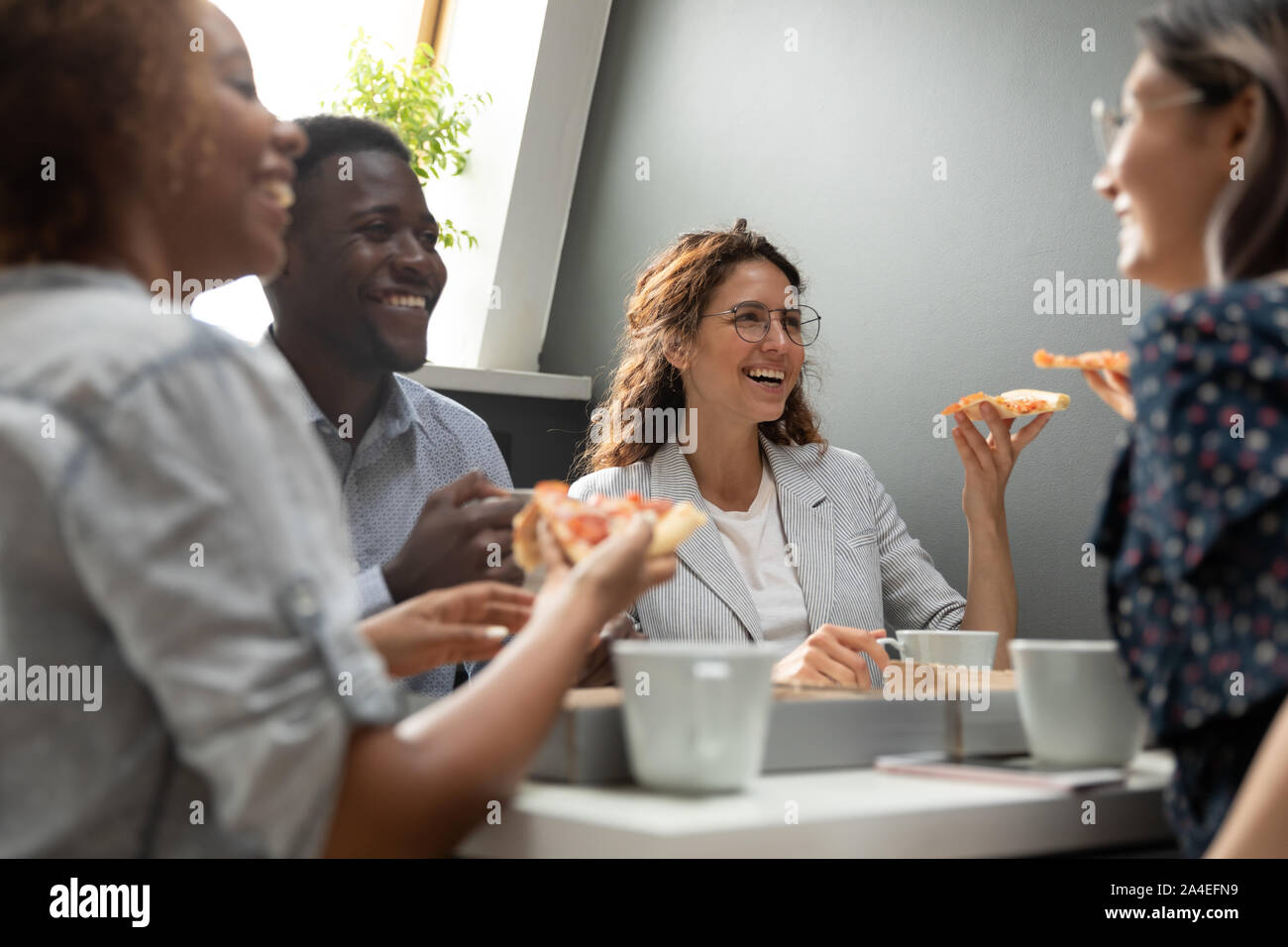 Multiracial company members having lunch eating pizza during break ...