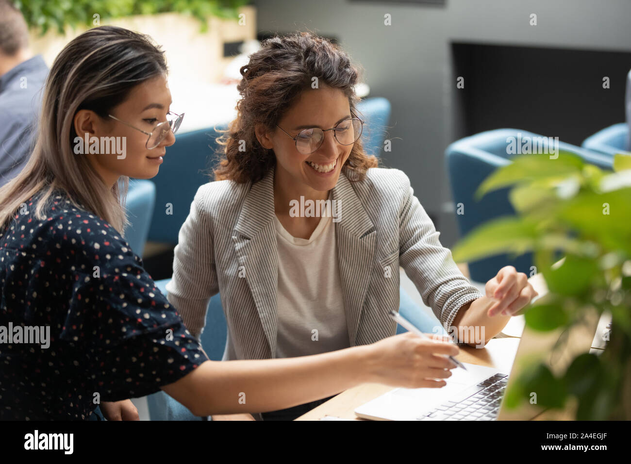 Women colleagues using computer working together in co-working space ...