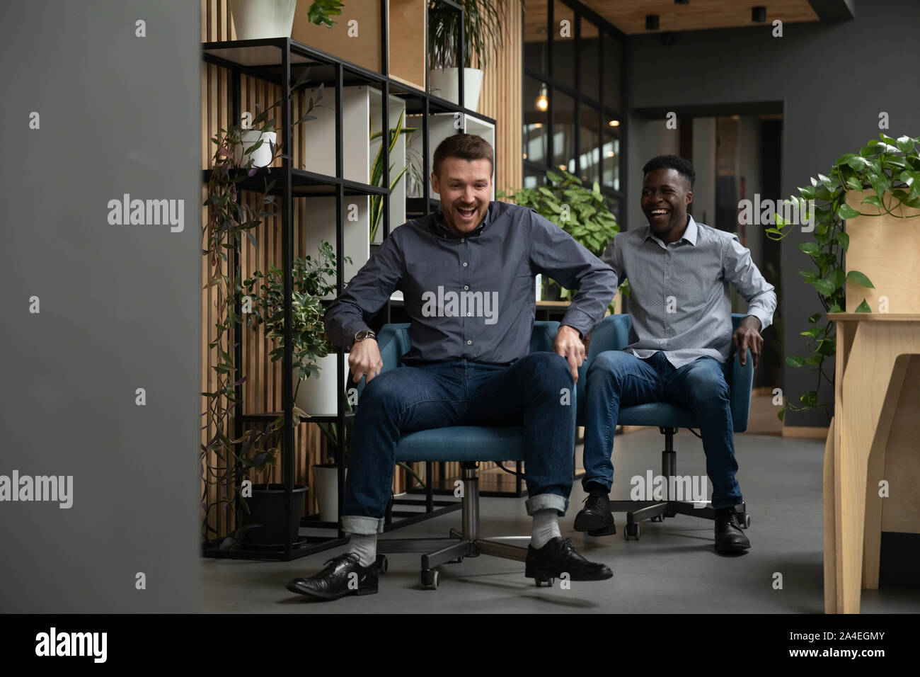 African and caucasian office workers having fun riding on chairs Stock ...