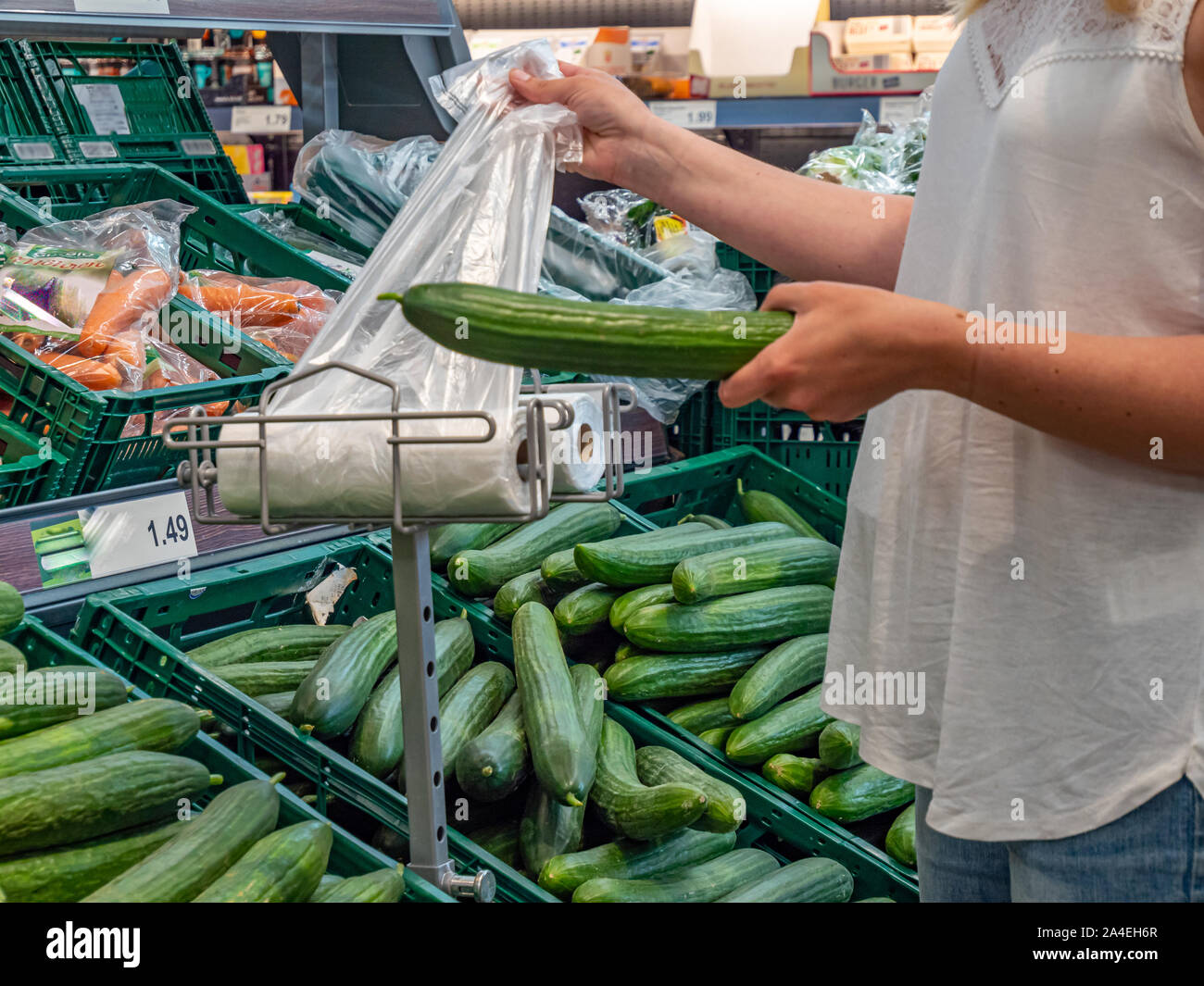 Customer is packing cucumber in plastic bag Stock Photo - Alamy