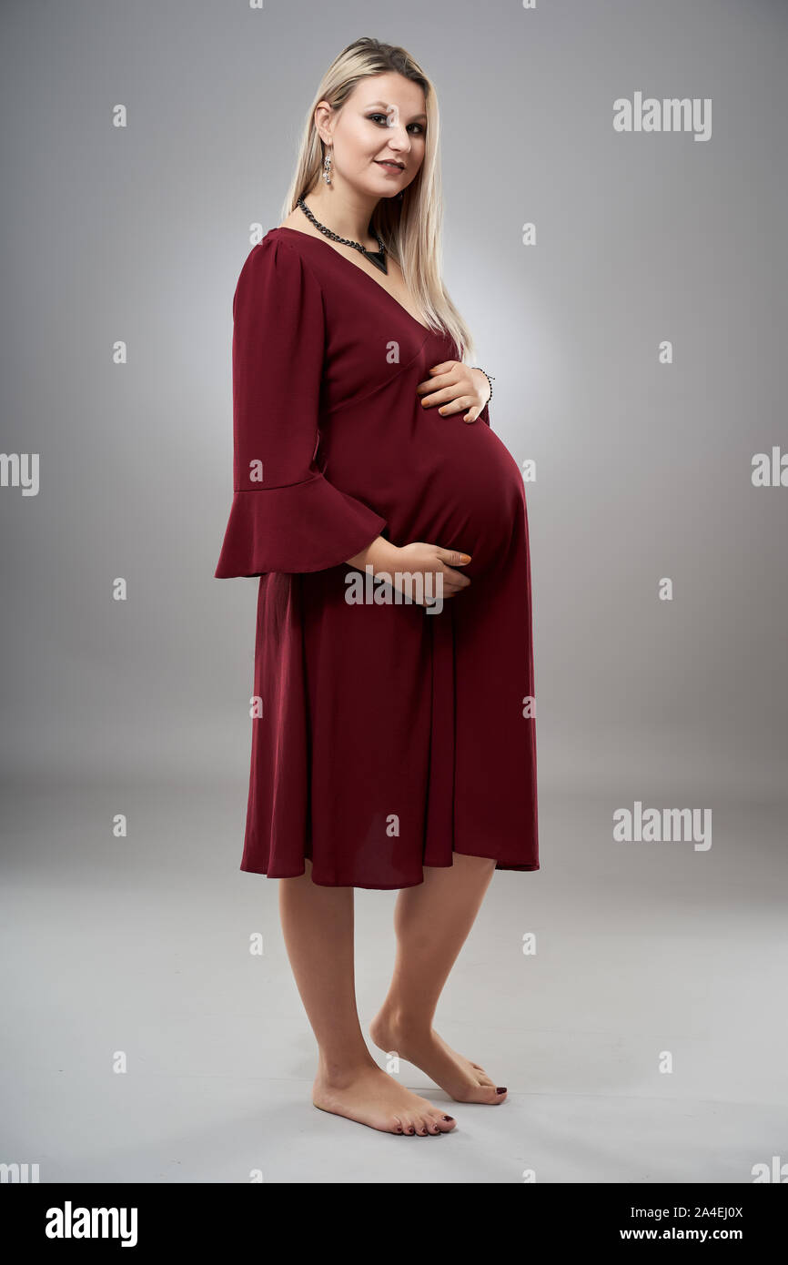 Studio full body portrait of a pregnant woman in red dress Stock Photo ...