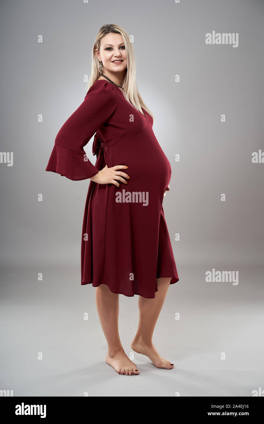 Studio full body portrait of a pregnant woman in red dress Stock Photo ...