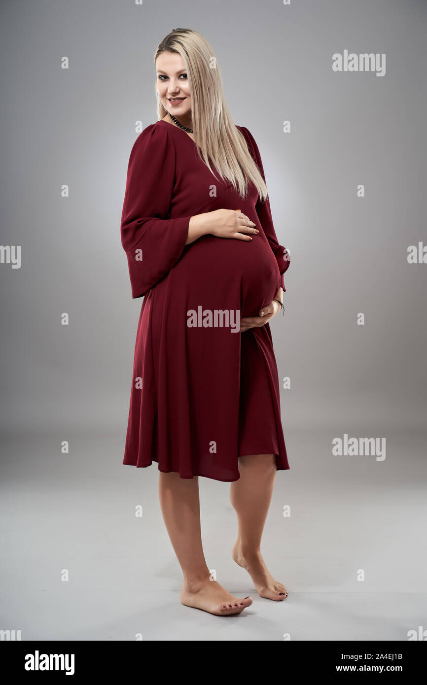 Studio full body portrait of a pregnant woman in red dress Stock Photo ...