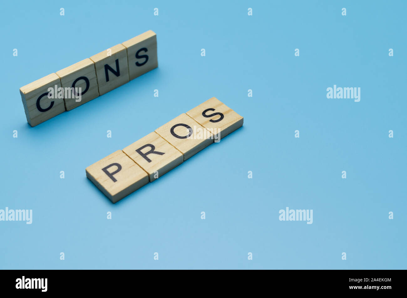 "Pros and Cons" word in the wooden block on blue background pointed by ...