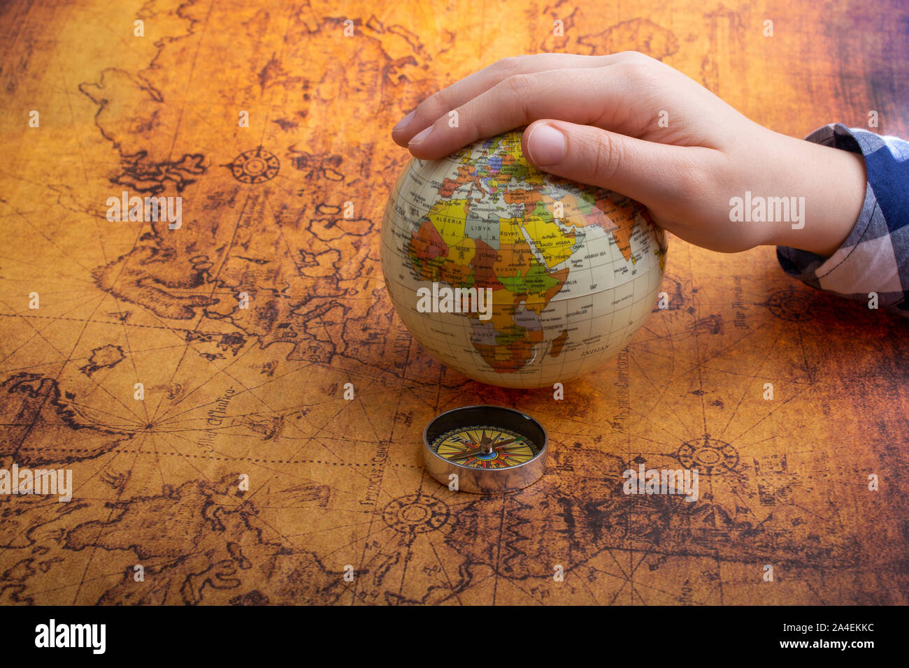 Compass on map beside a globe under hand Stock Photo - Alamy