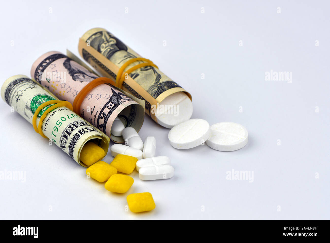 Dollar rolled up with pills flowing out isolated on white background ...