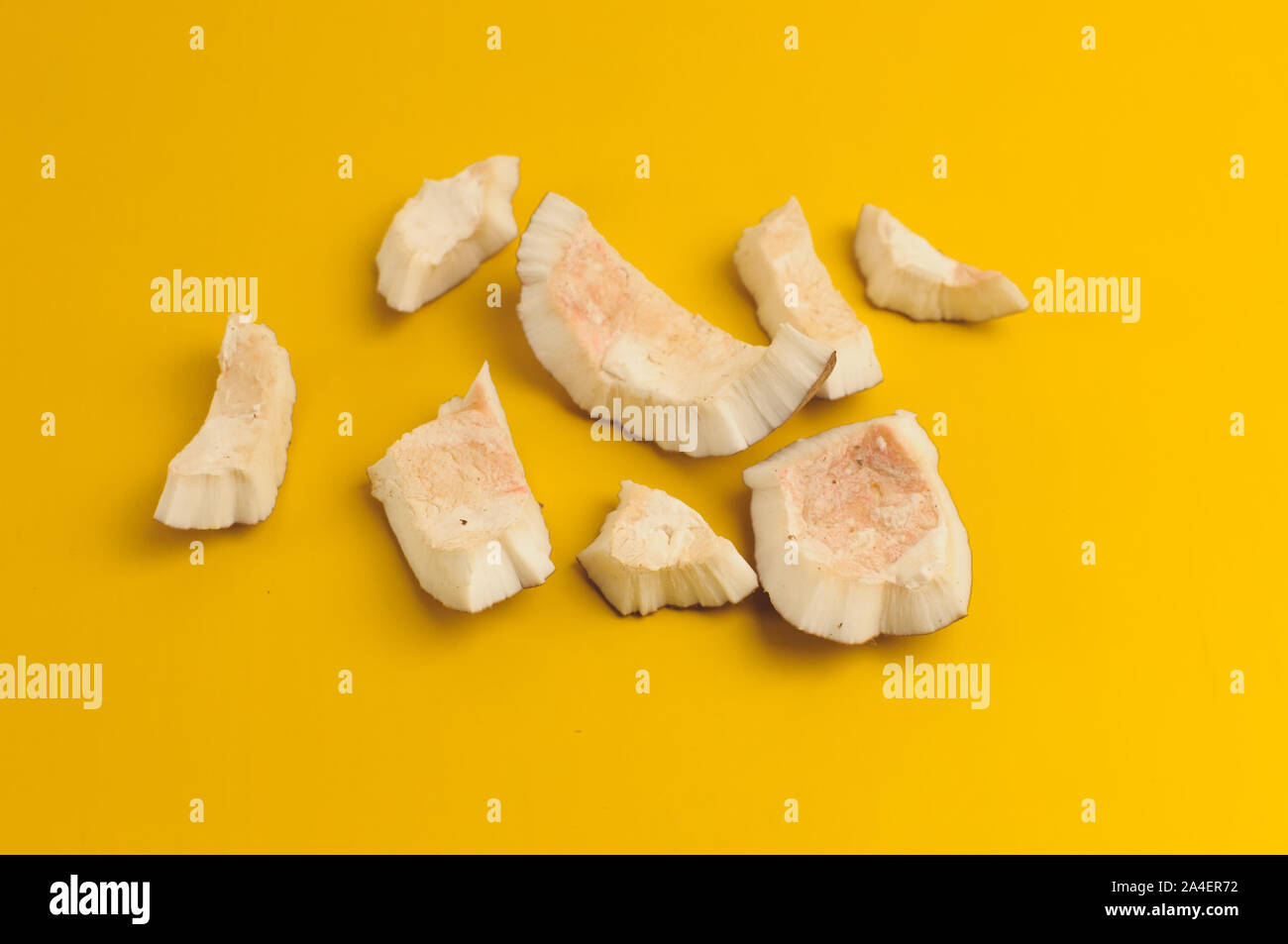 ugly organic broken rotten coconut on bright yellow background. pieces ...