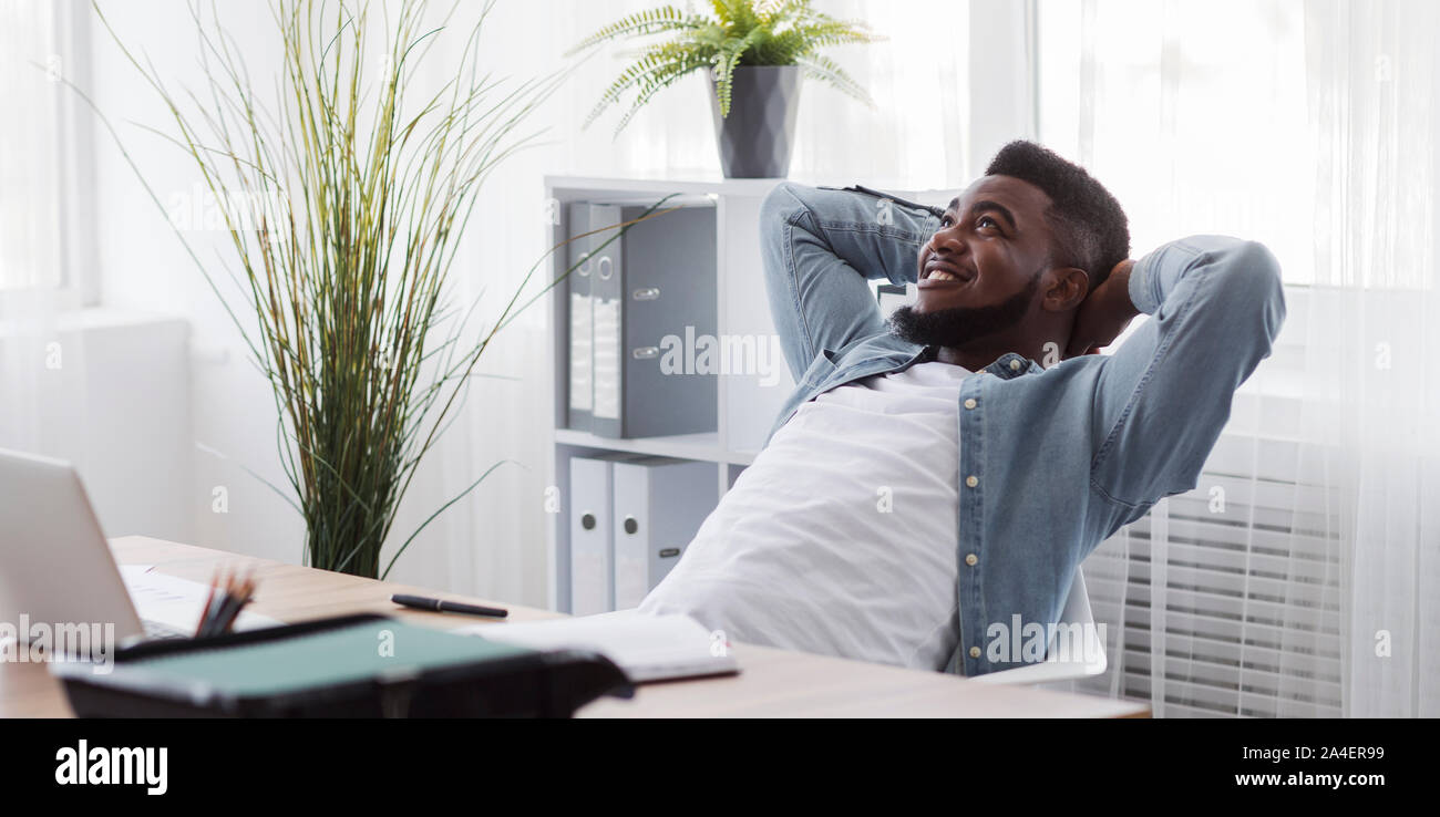 Black employee resting from office work, leaning back on chair Stock ...