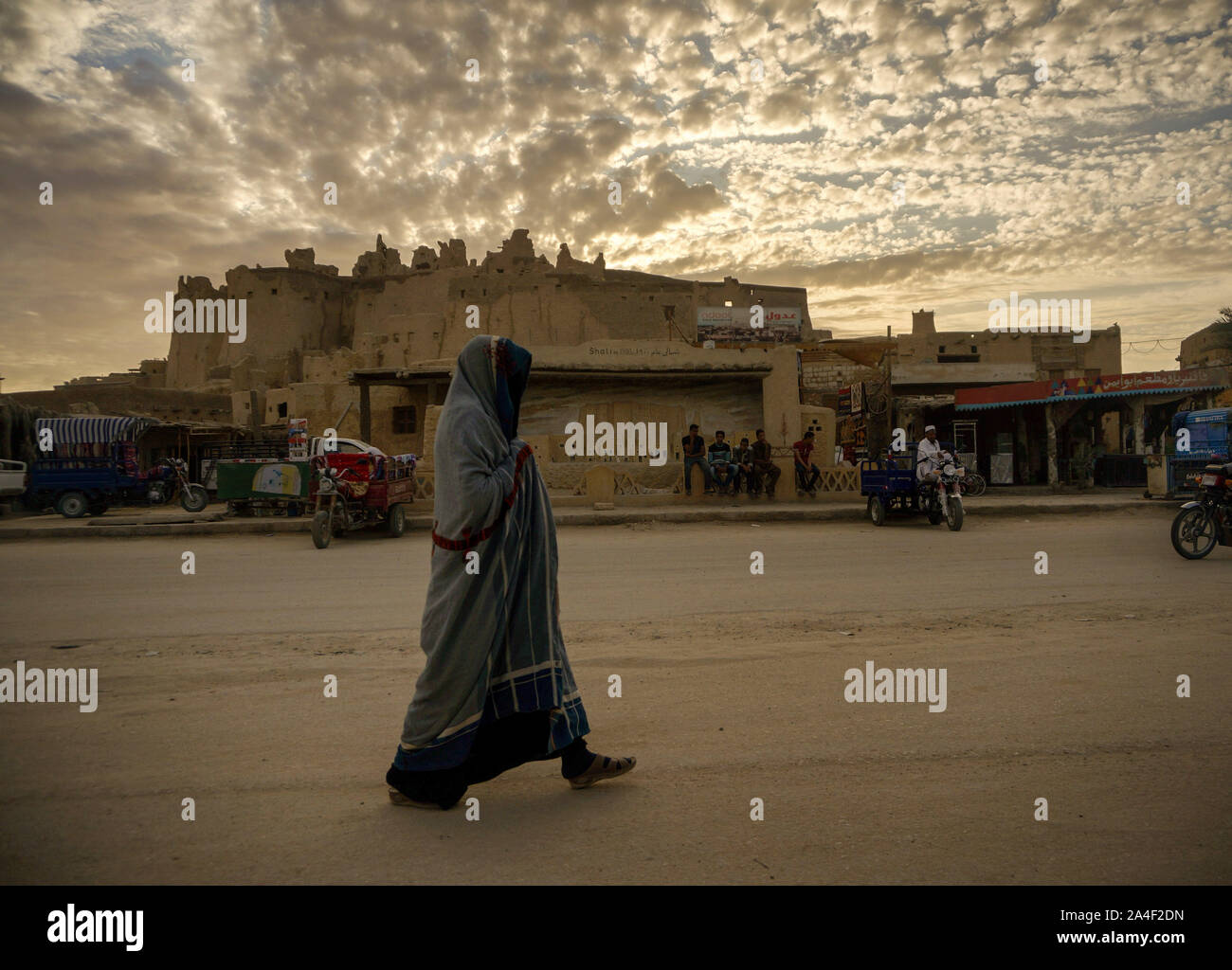 A veiled Berber Siwan woman walks by the fortress Shali of Siwa Oasis ...