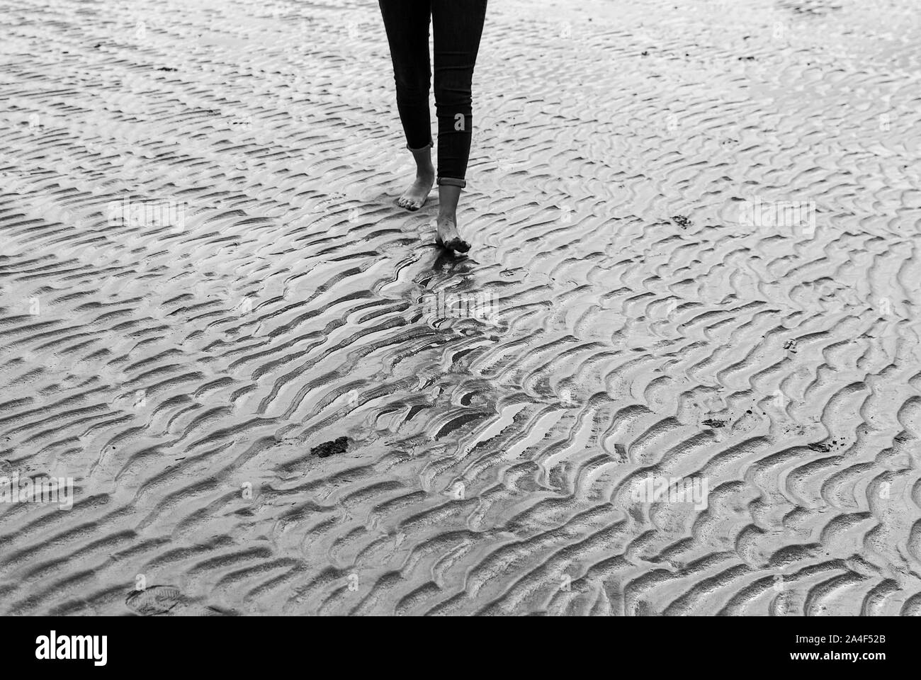 Young woman walking and playing on sandy beach and leaving footprints ...