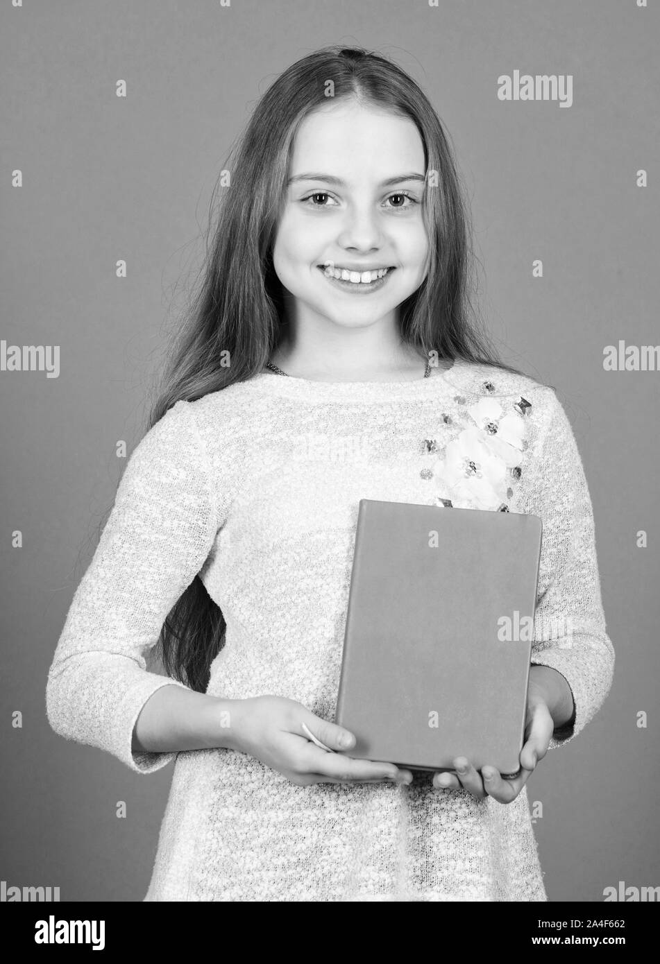 Her hobby is reading. Cute small child holding book for home reading ...