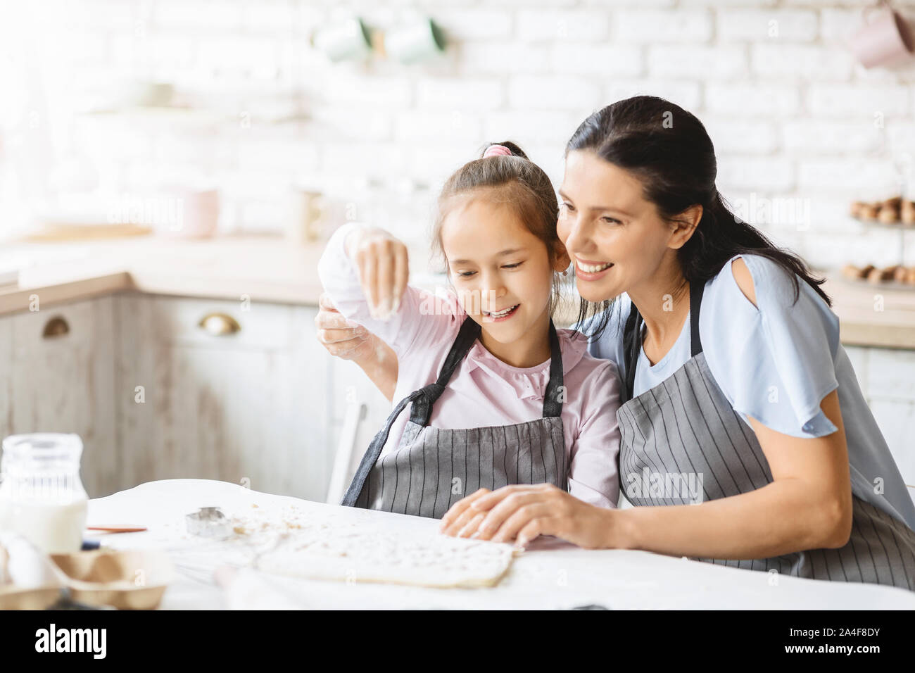 Pretty little girl and her attractive mom making cookies together Stock ...