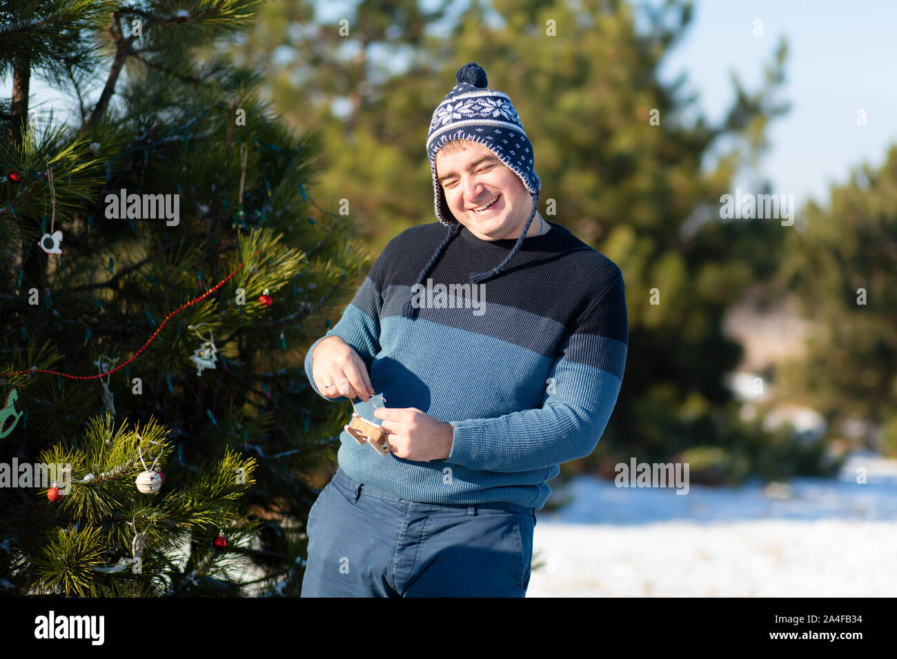 the guy decorates with a decorative toy and garland a green Christmas ...
