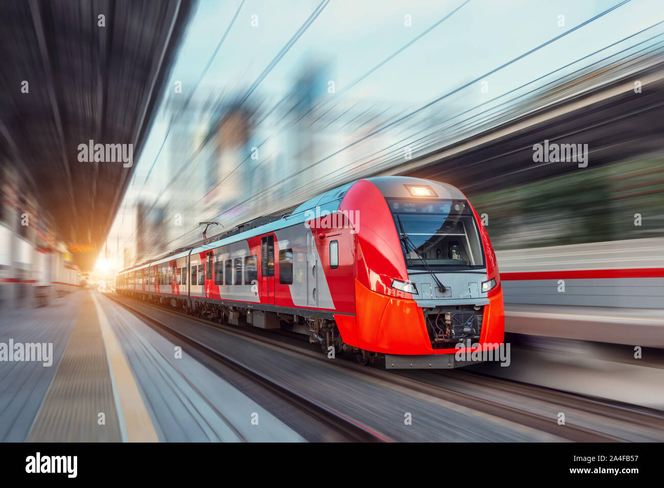 Electric passenger train drives at high speed among urban landscape ...