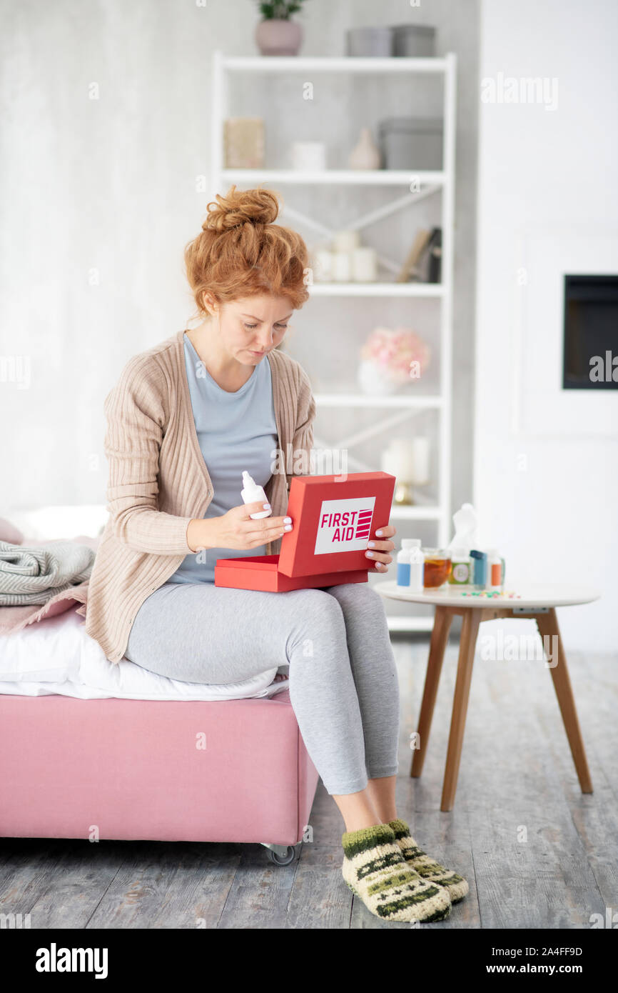 Woman holding first aid kit while suffering from cold Stock Photo - Alamy