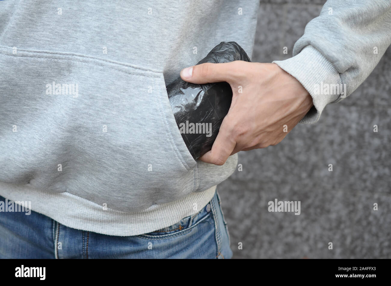 Drug dealer taking bag with cocaine out of hoodie pocket on dark tiles ...