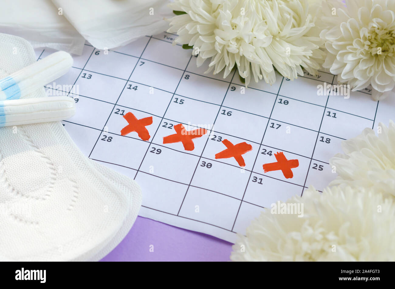 Menstrual pads and tampons on menstruation period calendar with white ...