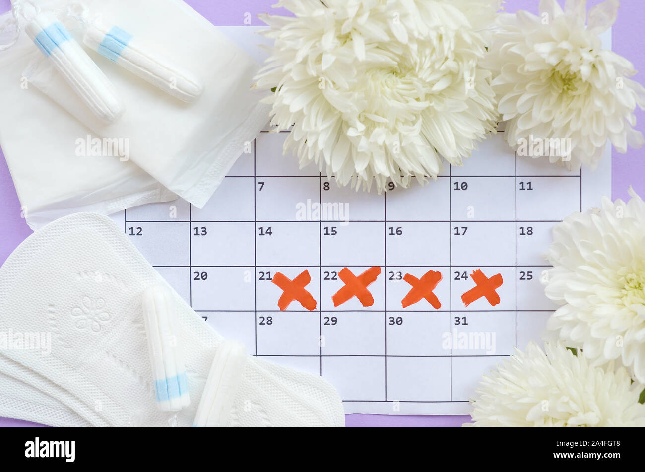 Menstrual pads and tampons on menstruation period calendar with white ...