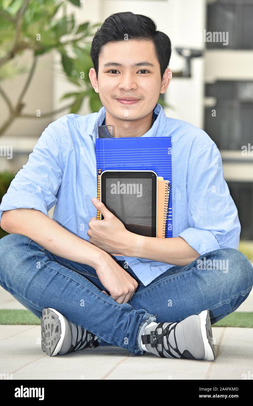 Happy Male Student Sitting On Campus Stock Photo - Alamy
