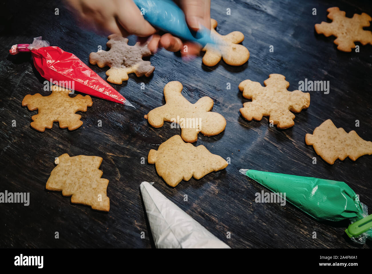 decorate Christmas gingerbread cookies using colored glaze on a dark ...
