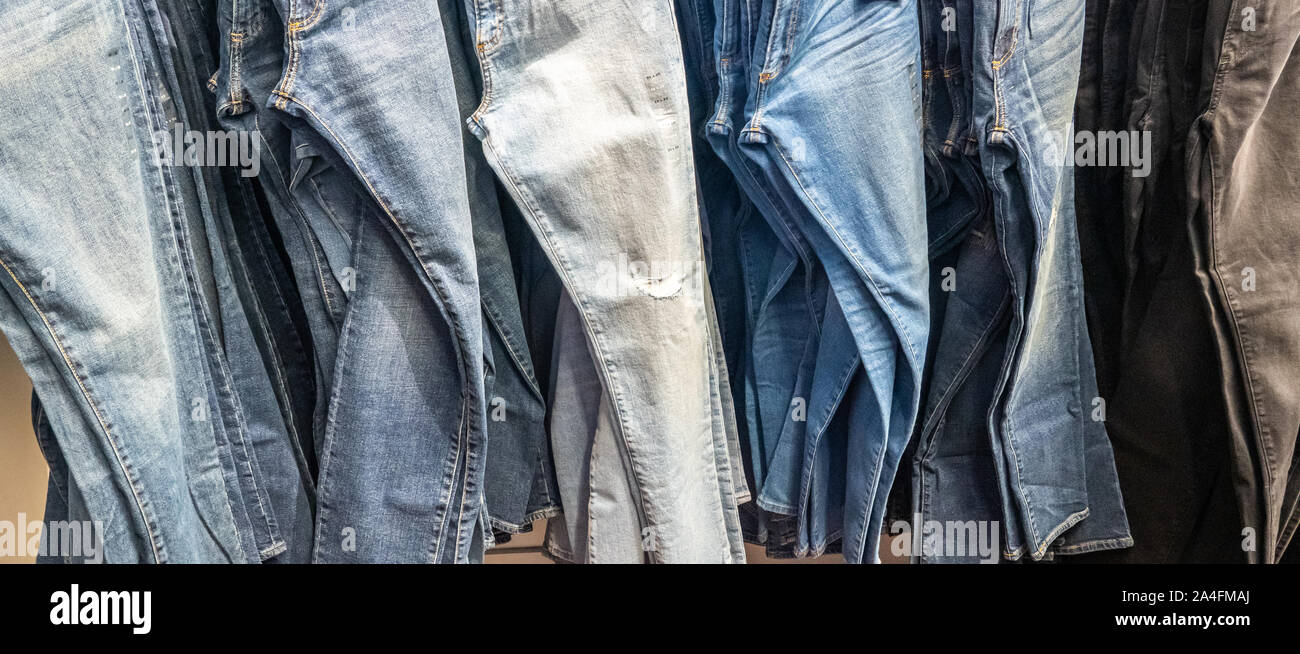 Jeans hanging on a rack. Row of denim pants Stock Photo - Alamy