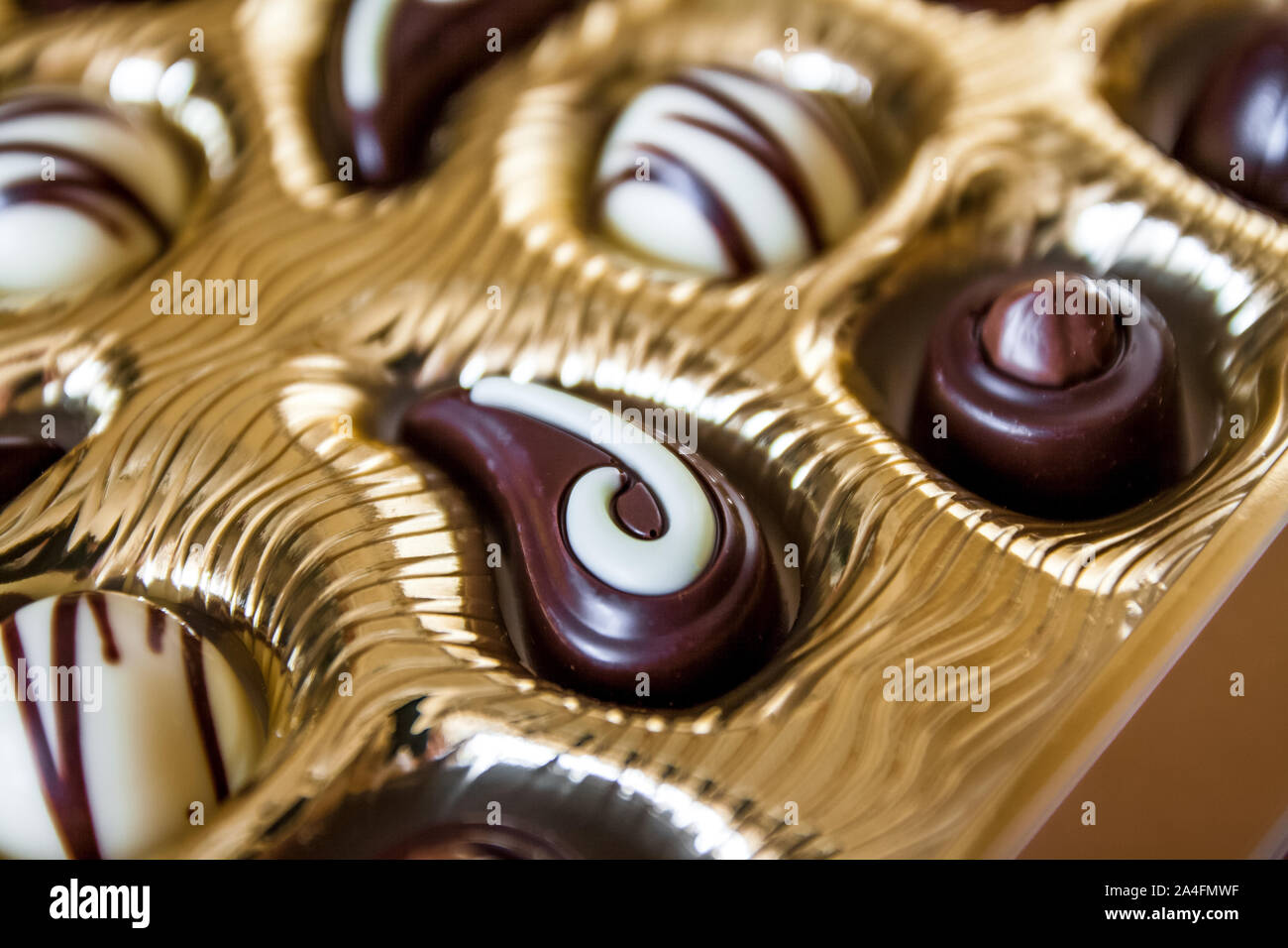 Chocolate candies of different shapes in a gold box, a perspective view ...