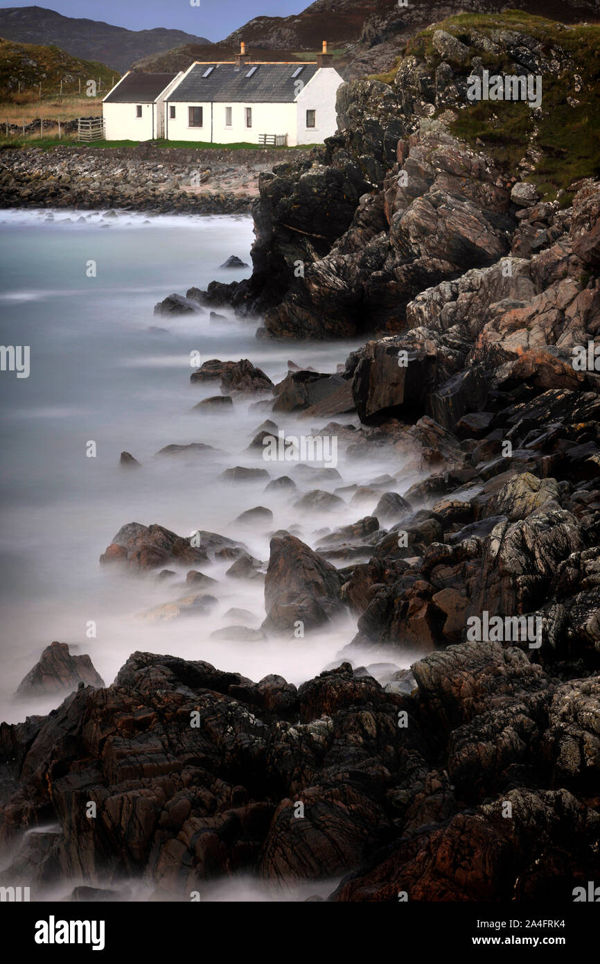 View of the rocky coast and white cottage at Clashnessie Bay, Assynt ...