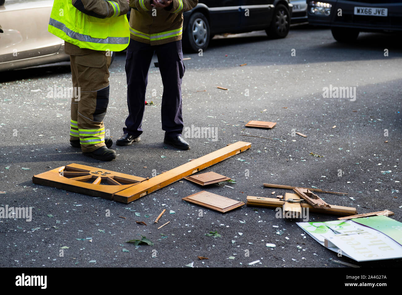 Firefighters stand over broken glass and a front door that have been ...