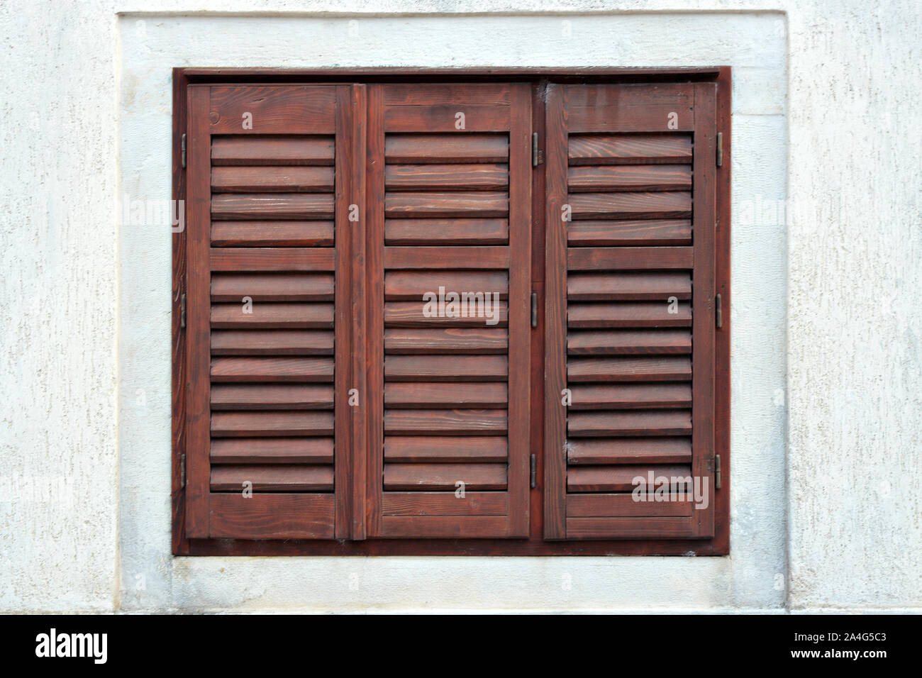 Window covered with brown wooden shutters. From a series of windows of ...