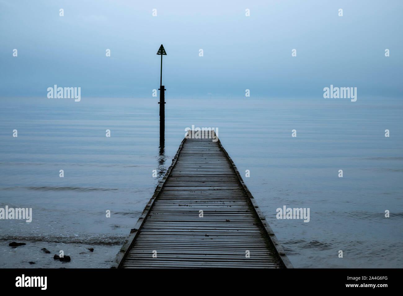 Old wooden single pier leading into a foggy ocean with little variation ...