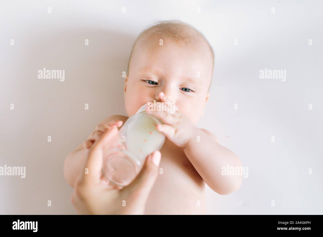 A portrait of cute newborn baby being fed by her mother using bottle ...