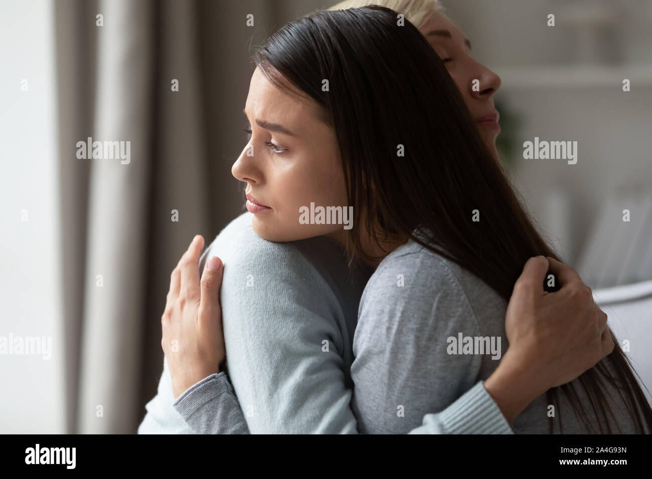 Side view caring middle aged woman soothing sad millennial daughter ...