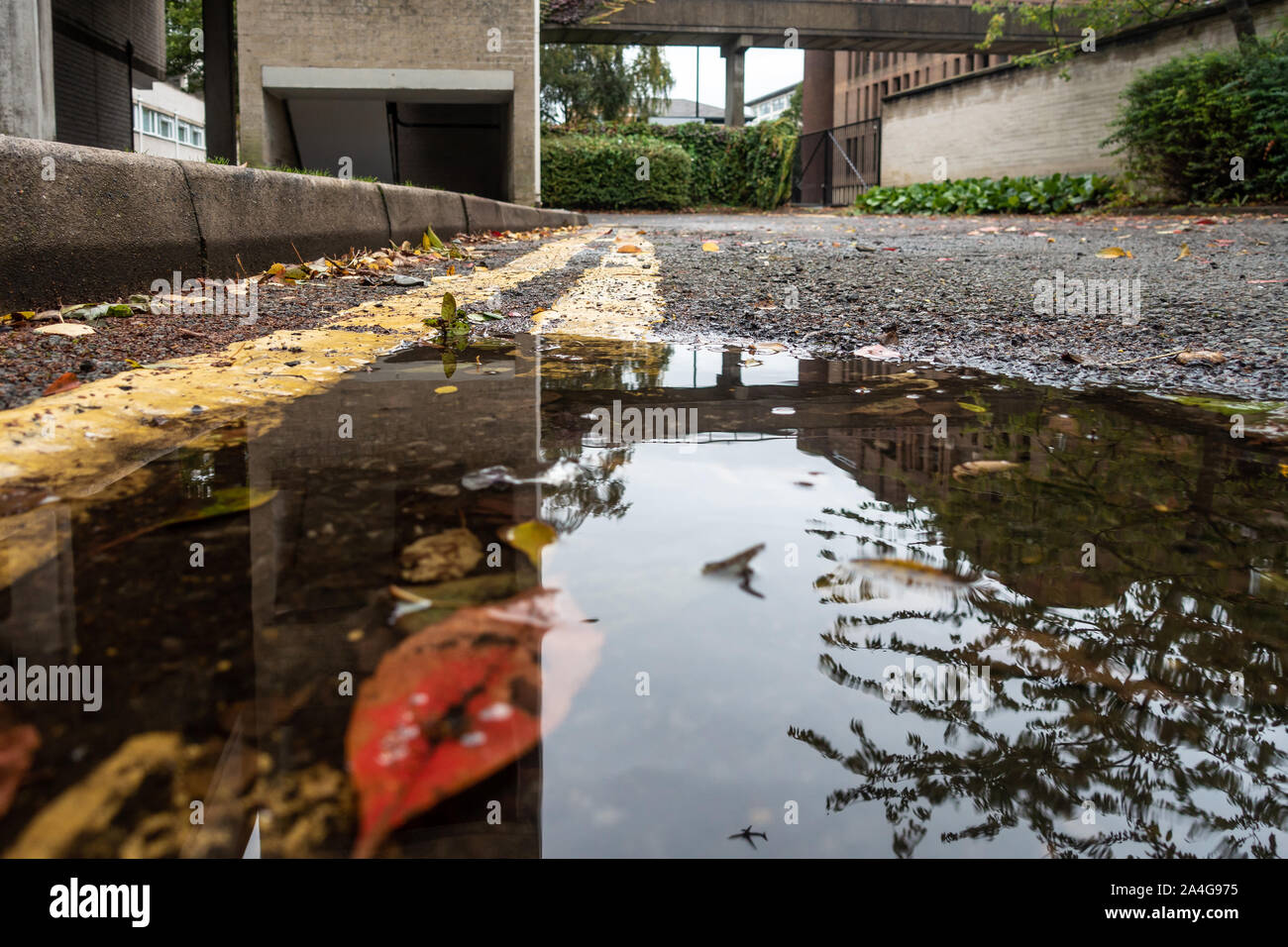 A puddle at the side of a road with double yellow lines running through ...