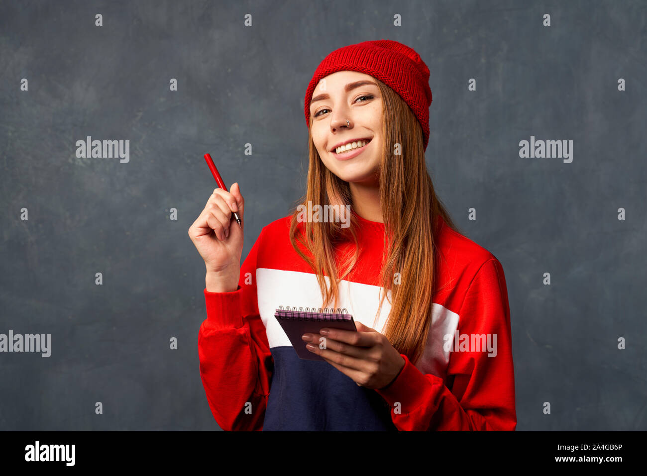 girl holds notepad, pen isolated on textured wall Stock Photo - Alamy
