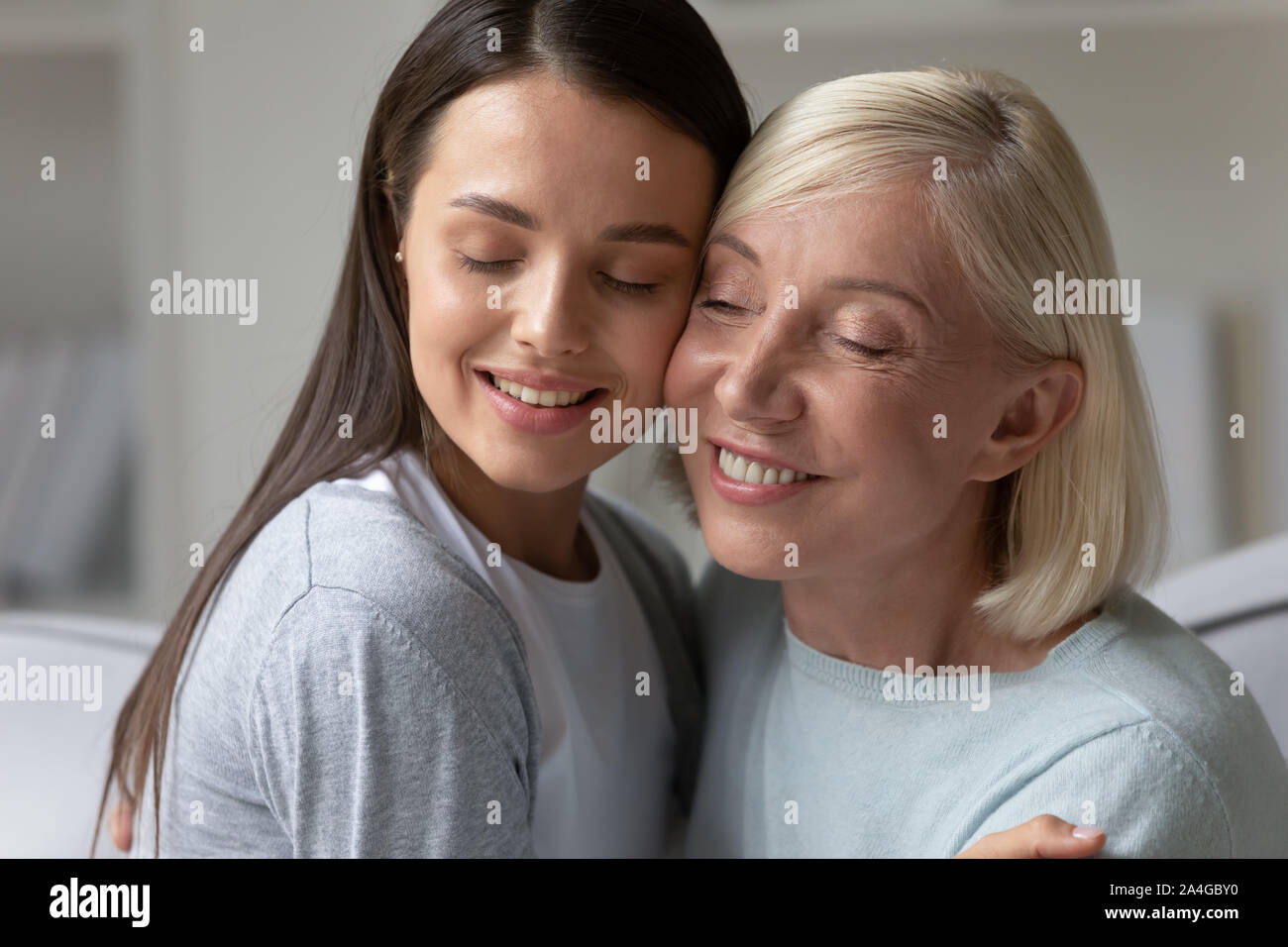 Happy two generations cuddling hugging in living room Stock Photo - Alamy