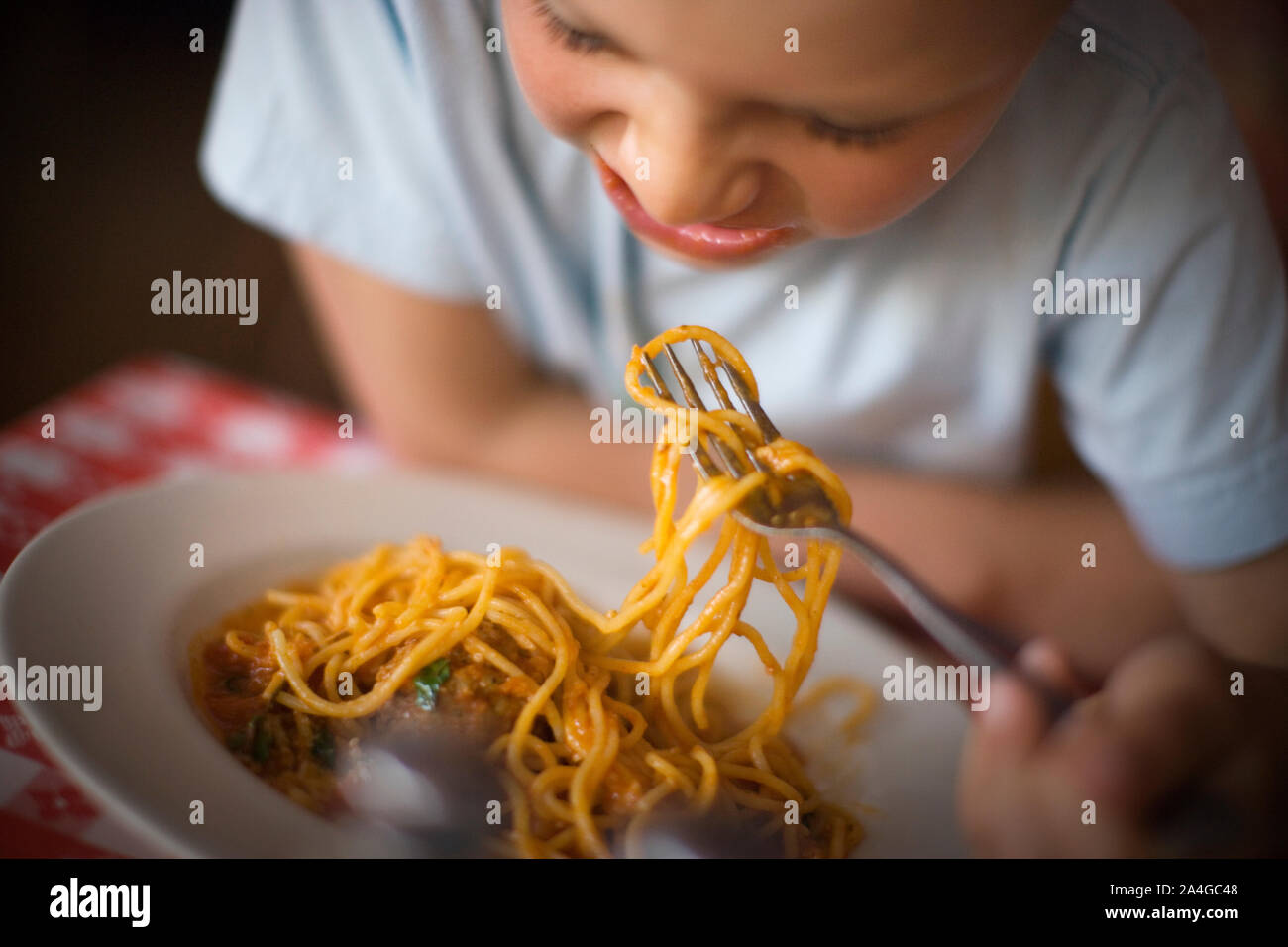 Boy eating spaghetti at a dinner table Stock Photo - Alamy