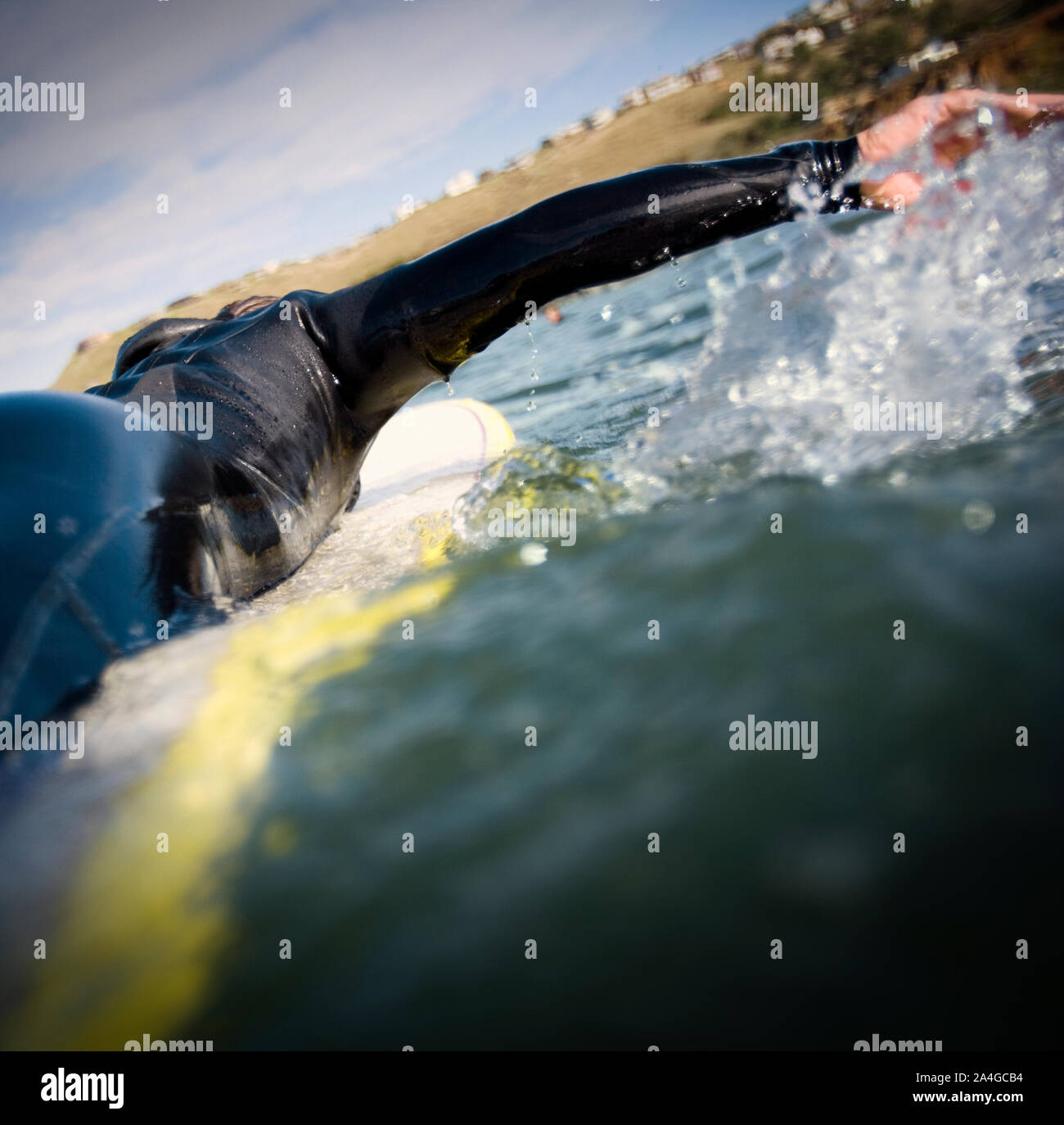 Surfer paddling through surf while lying on his surfboard Stock Photo ...