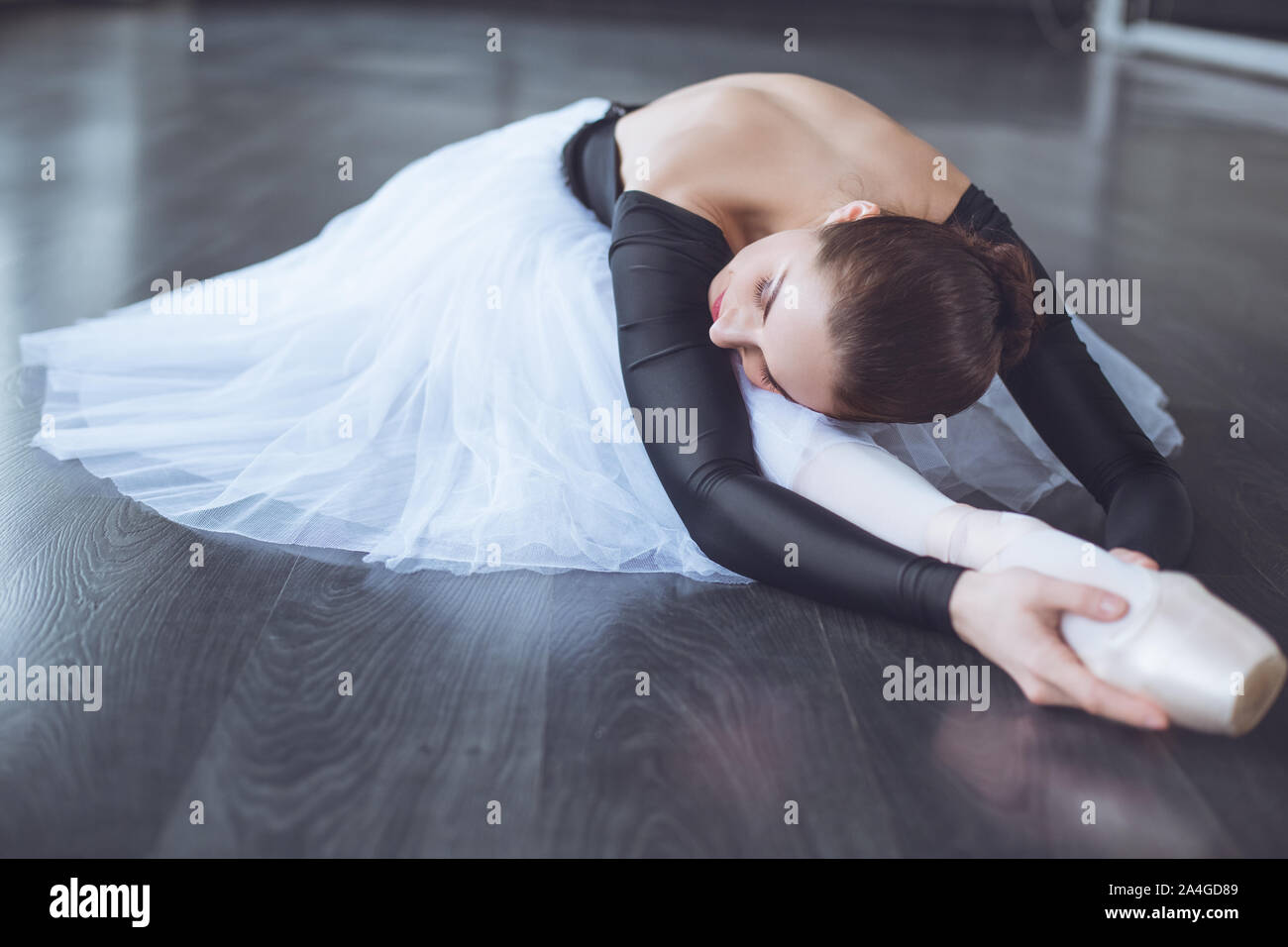 Young ballet dancer practice in studio sitting stretching on the floor ...