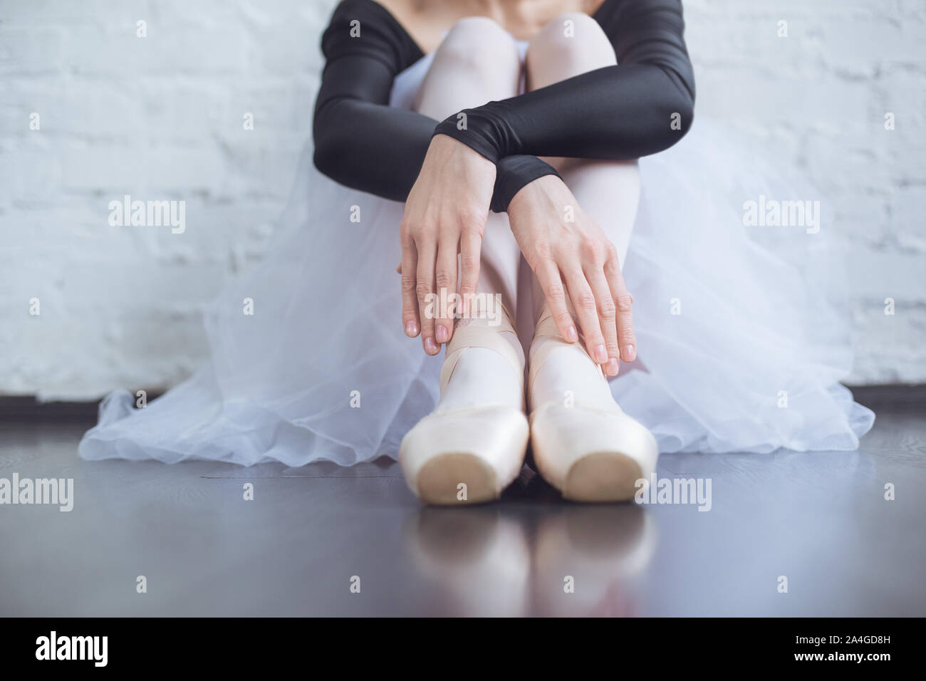 Young ballet dancer sitting leaning white wall in studio active ...
