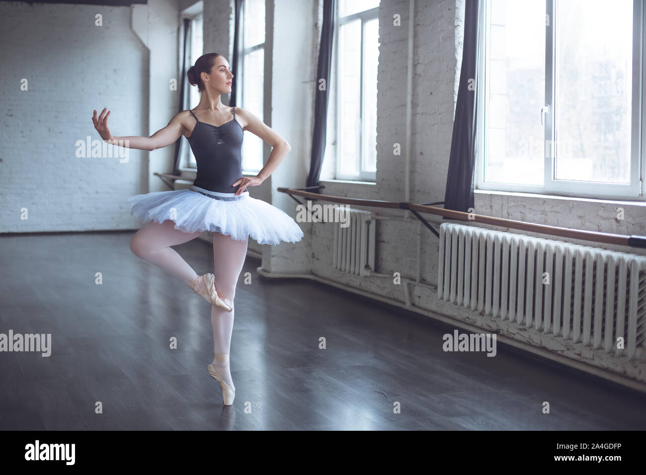 Young ballet dancer practice movement looking out the window in studio ...