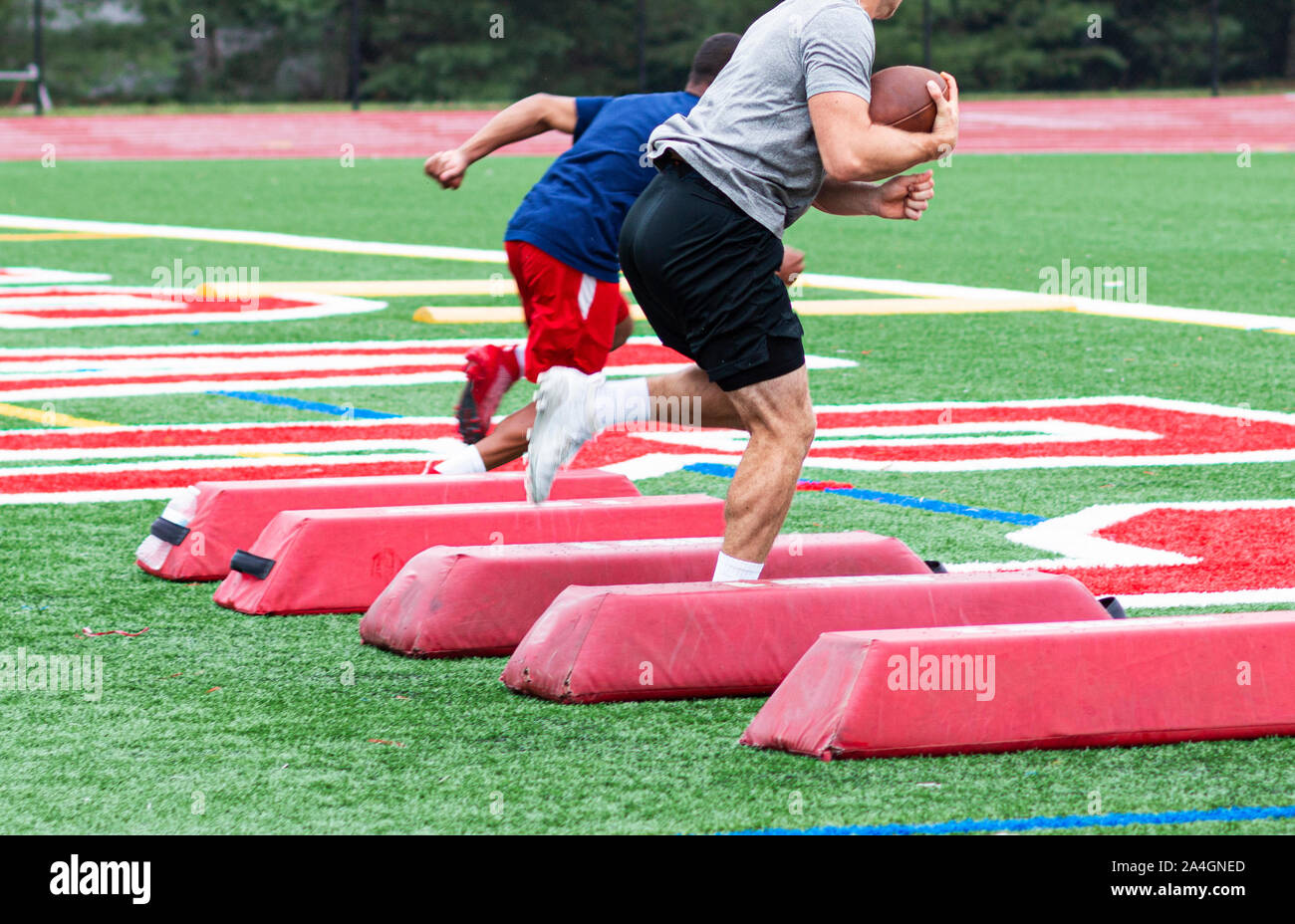 Two football players are running sideways while avoiding red barriers ...