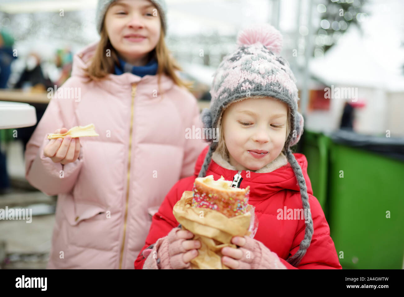 Two cute young sisters eating Czech trdelnik on traditional Christmas ...