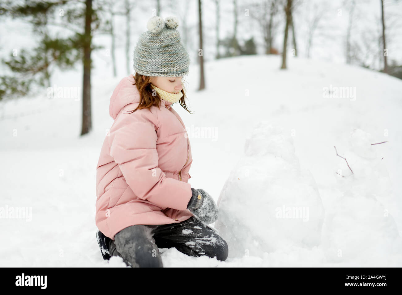 Adorable young girl having fun in beautiful winter park during snowfall ...