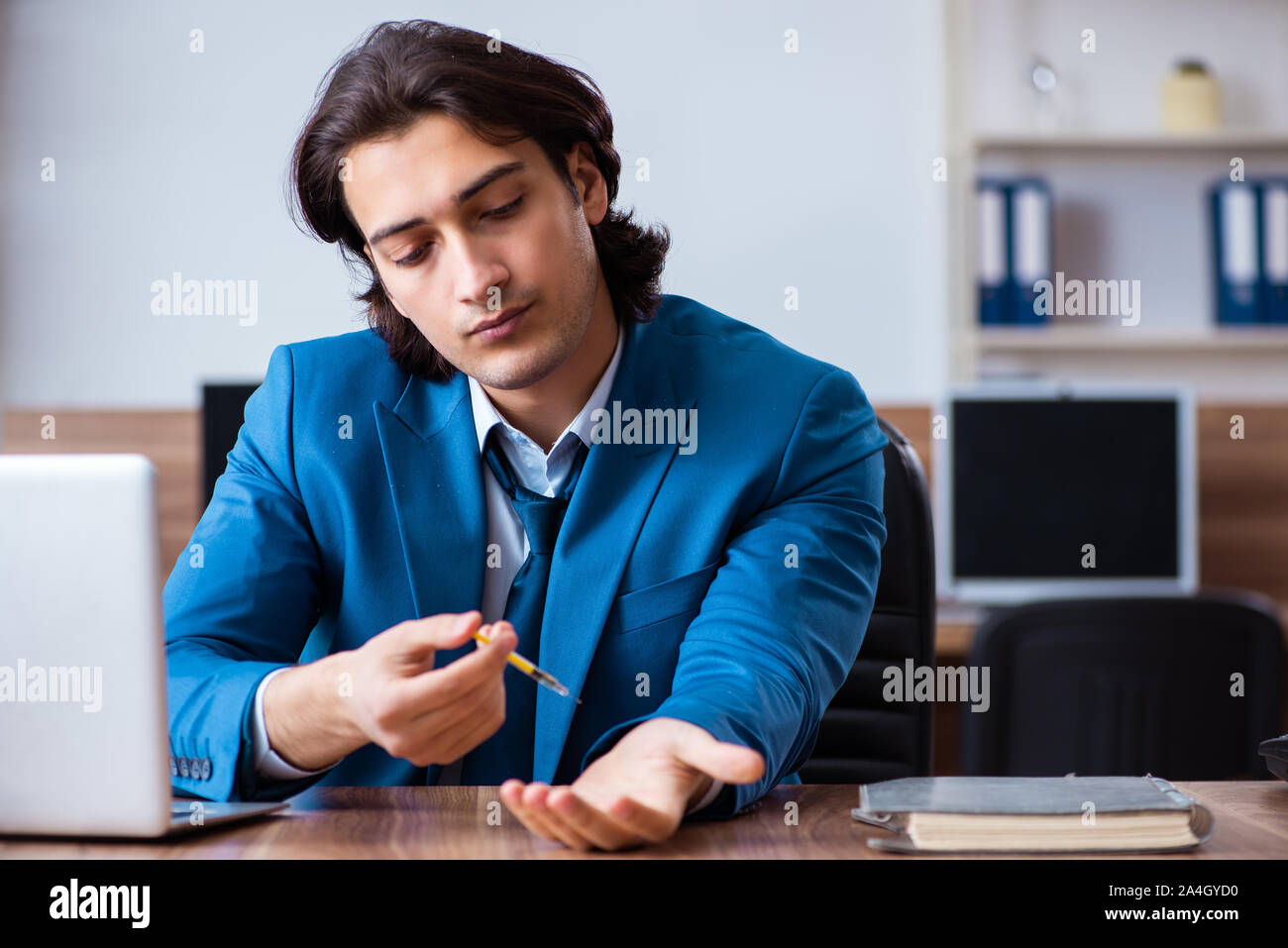 The young man having problems with narcotics at workplace Stock Photo ...