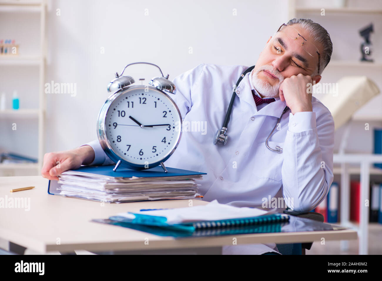 The old male doctor working in the clinic Stock Photo - Alamy