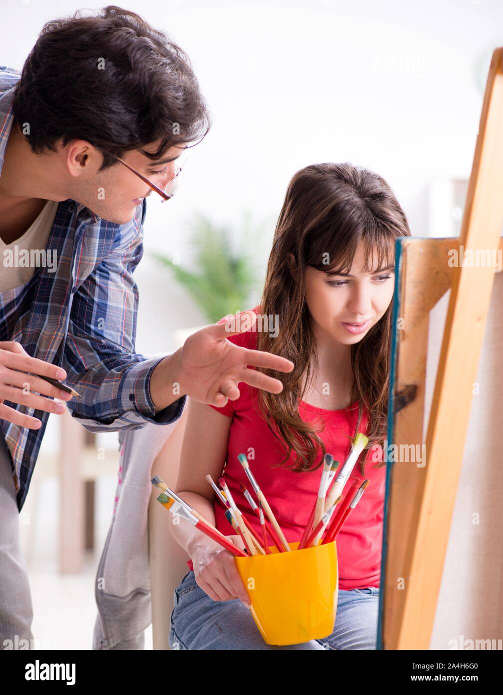The artist coaching student in painting class in studio Stock Photo - Alamy